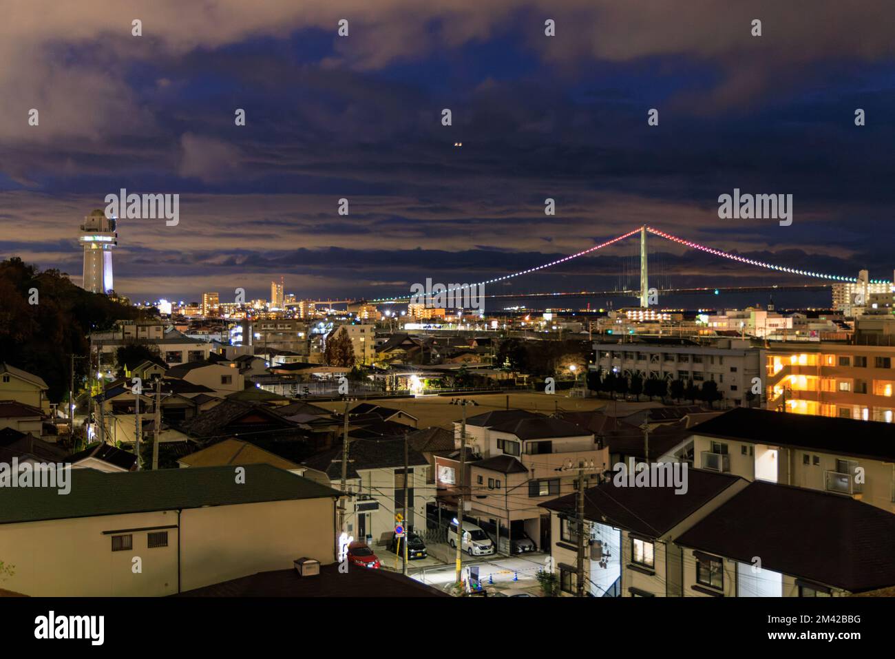 Colorful lights on suspension bridge with lights from small town in ...