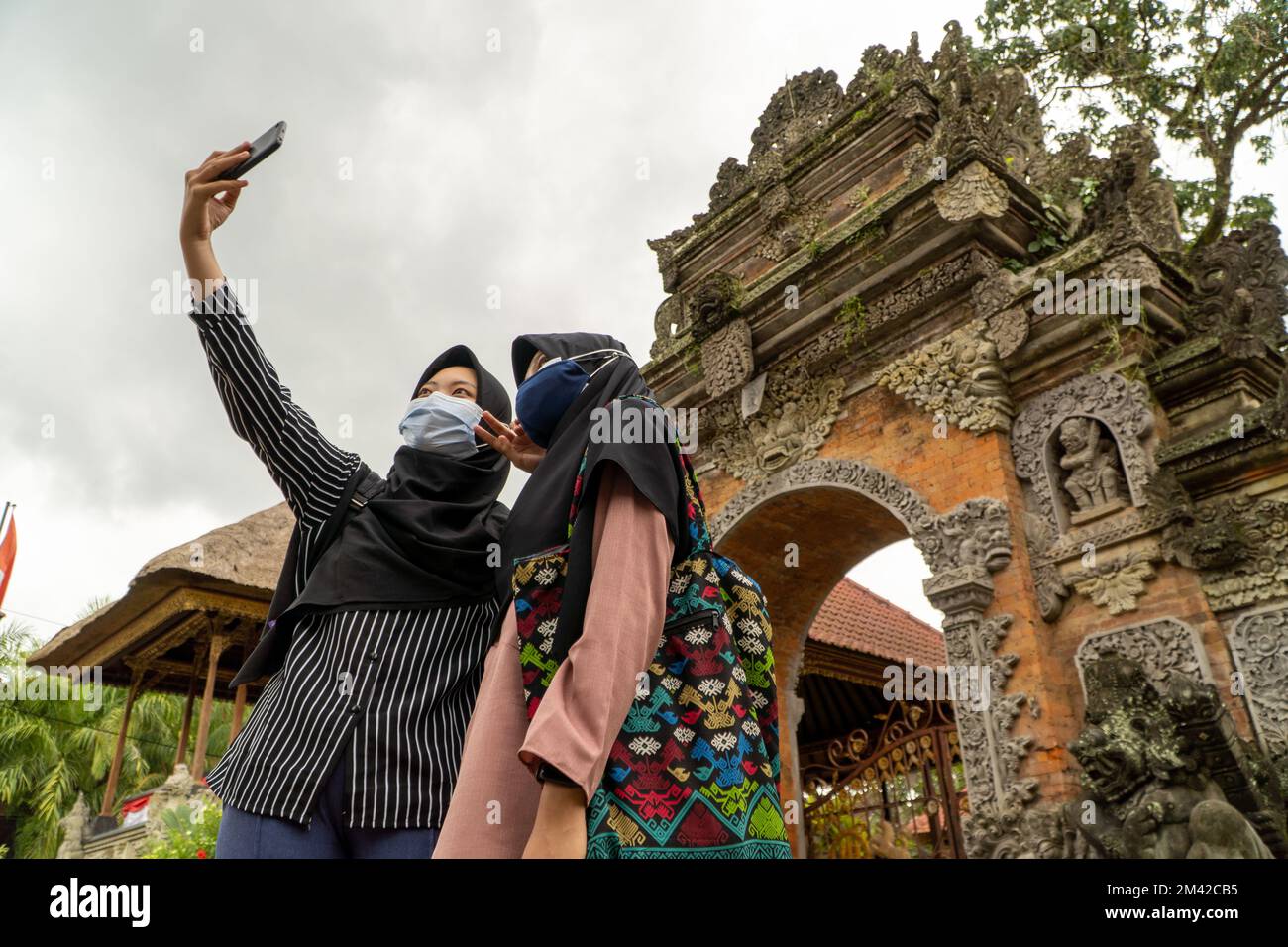 two Muslim female tourists wearing headscarves or hijab, are taking ...