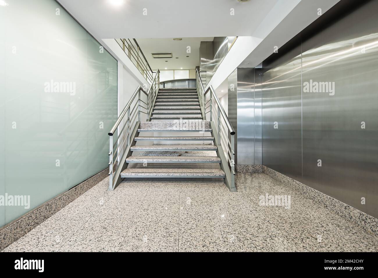 An antechamber with glass and stainless steel walls and stairs going up ...