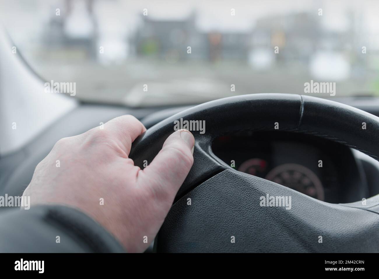 Hand on a car steering wheel. Windshield and perspective of the road ...