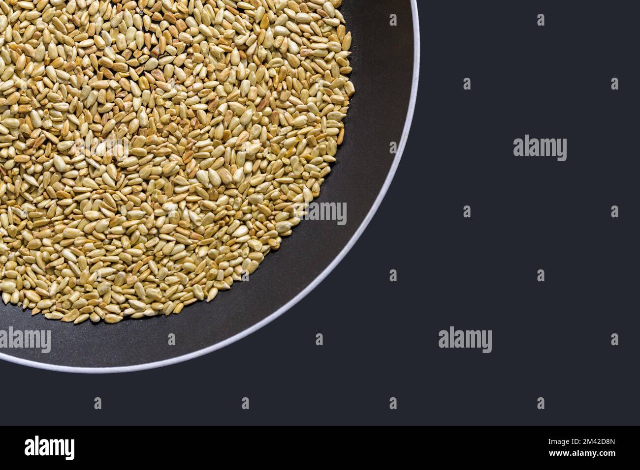Sunflower seeds in a pan. Peeled roasted sunflower seeds on a black ...