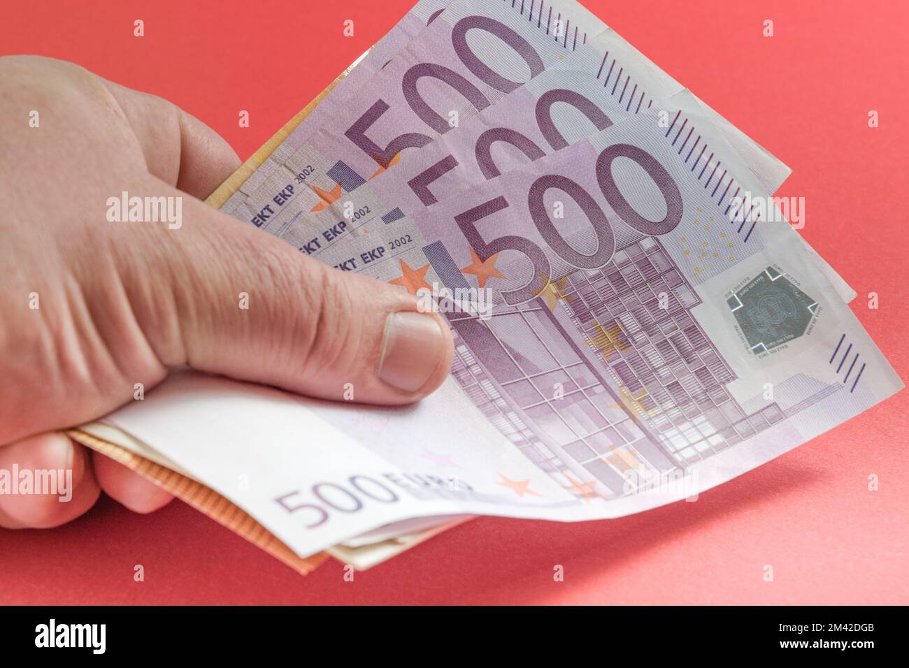 Euro banknotes in the hand. Red background Stock Photo - Alamy