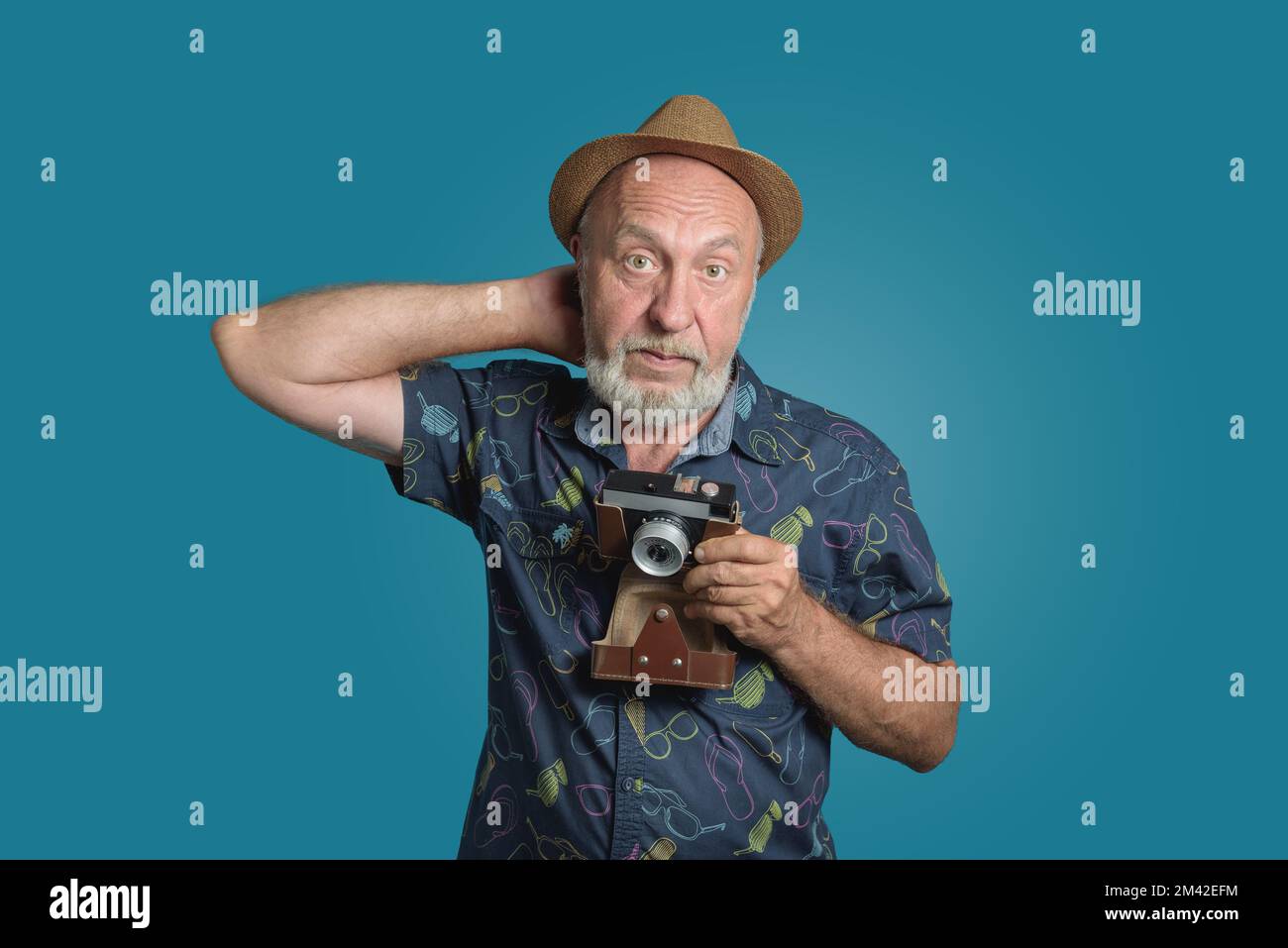 Senior photographer with retro camera scratching head. Mooved his straw ...