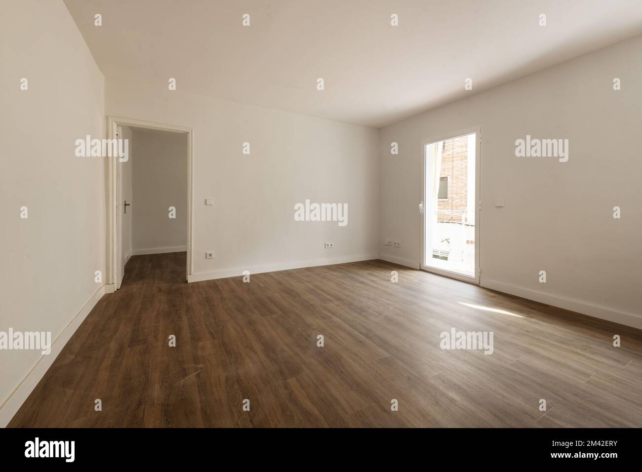 Empty room with dark wooden floors and access doors to other rooms and ...