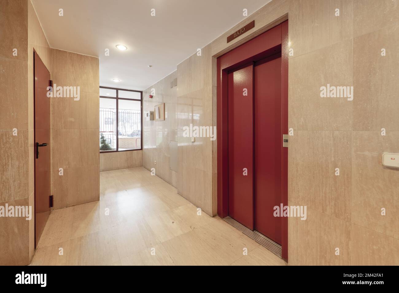 Portal of a house with tiles and marble floors and an elevator with red ...