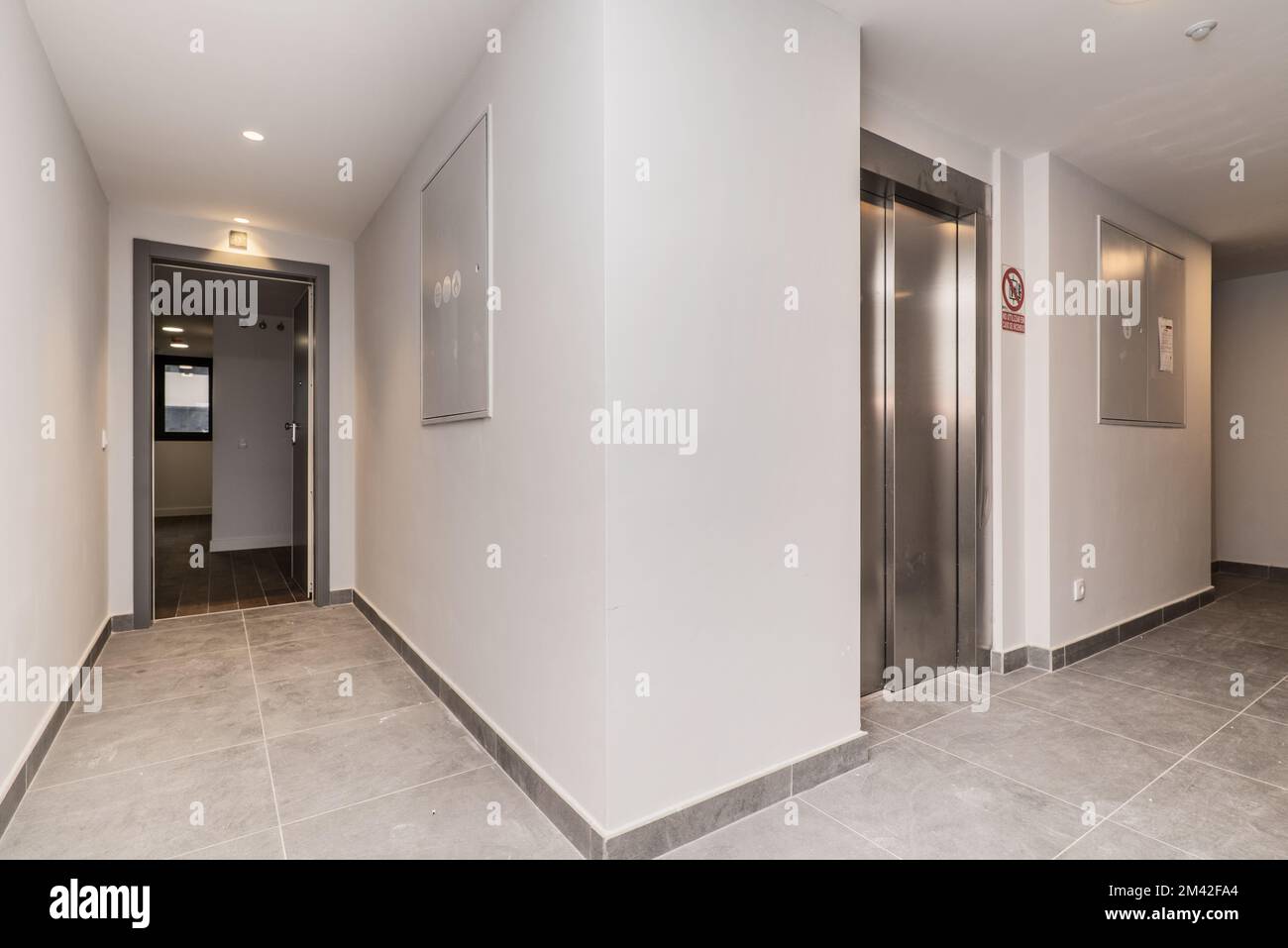 Portal of a house with white walls, gray floors and elevator with metal ...