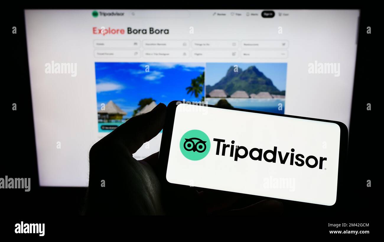 Person holding mobile phone with logo of American travel company ...