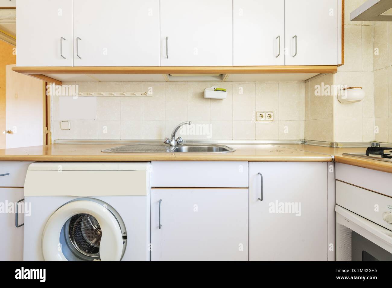 front of a kitchen with white cabinets, washing machine and wooden ...