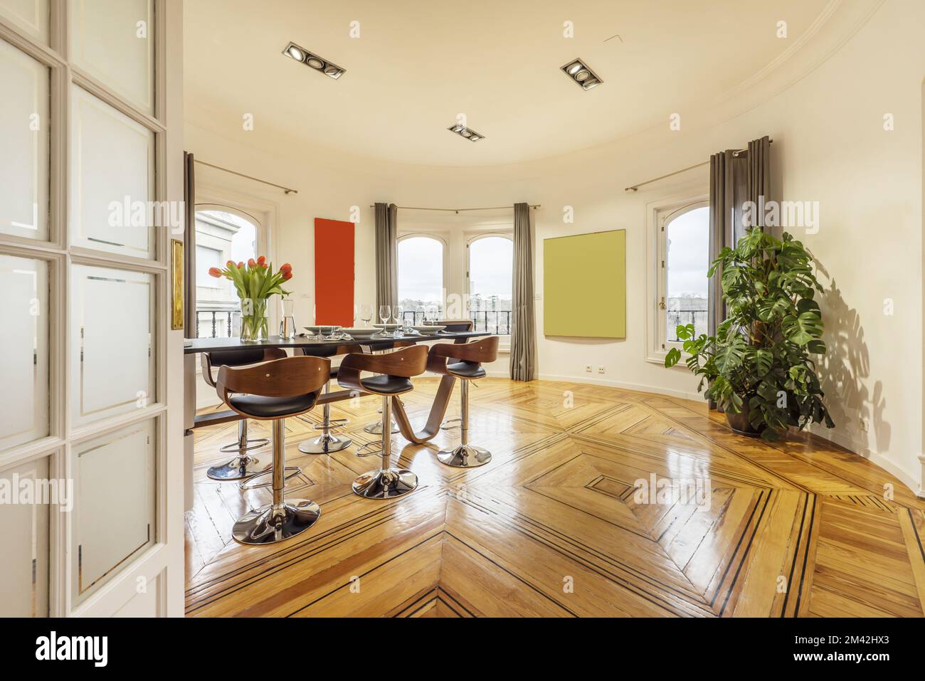 A large circular room with floor-to-ceiling windows facing the street ...