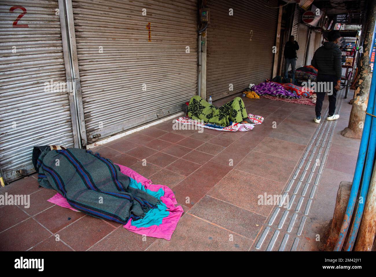 Homeless people sleeping along a footpath during cold winter morning ...