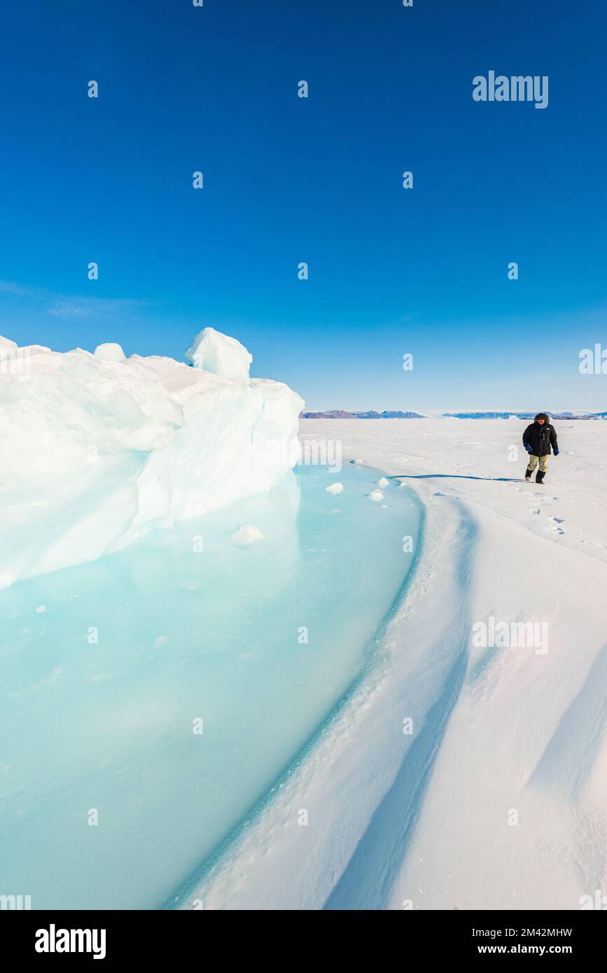 Tourist walking besides iceberg frozen on sea Stock Photo - Alamy