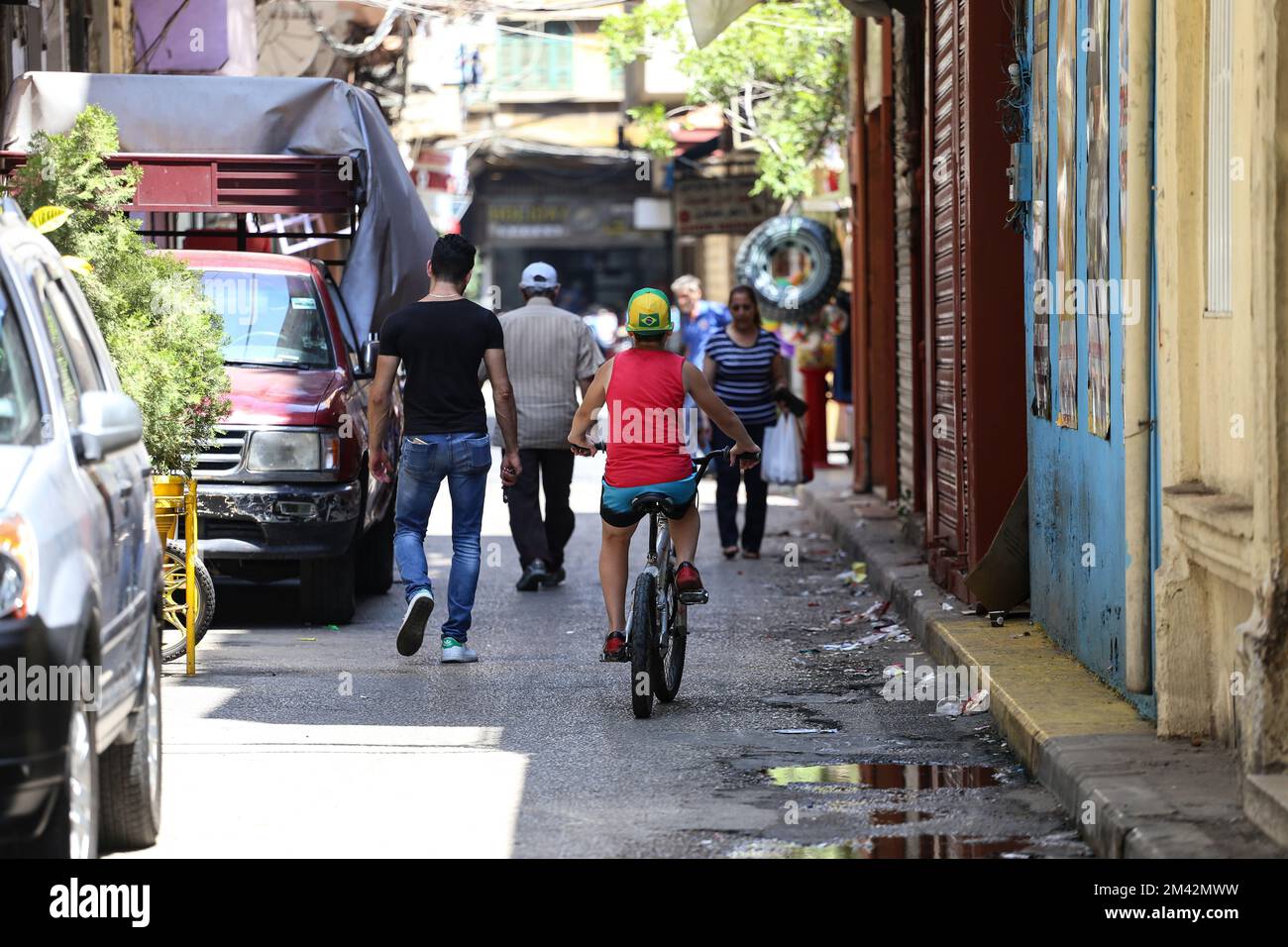 A busy street in Bourj Hammoud with people walking and a kid riding a ...