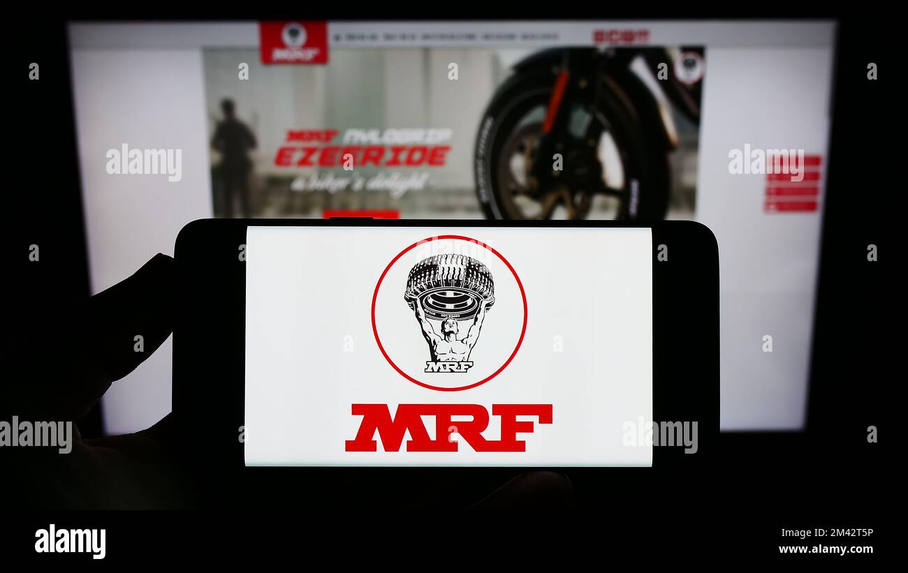 Person holding smartphone with logo of Indian company Madras Rubber Factory (MRF Tyres) on ...