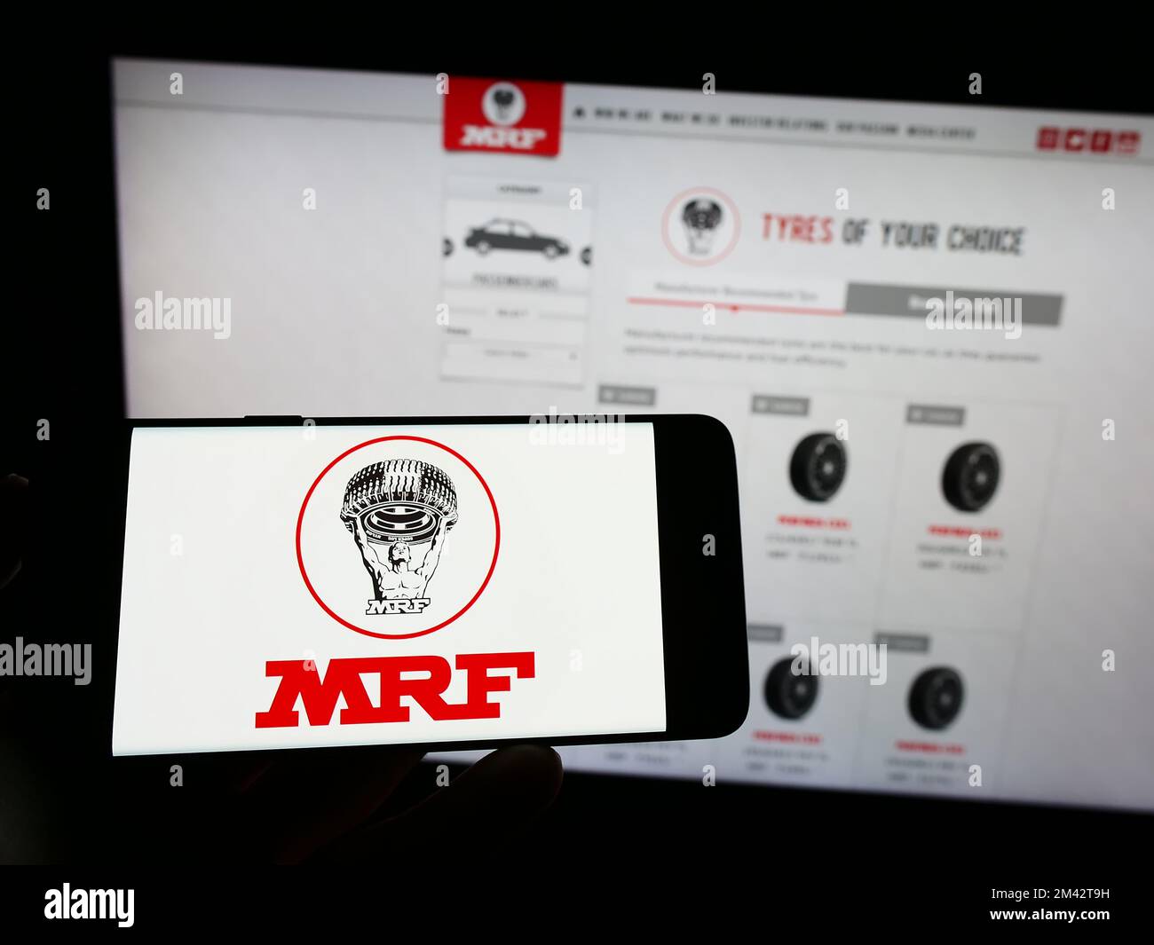 Person holding mobile phone with logo of Indian company Madras Rubber ...