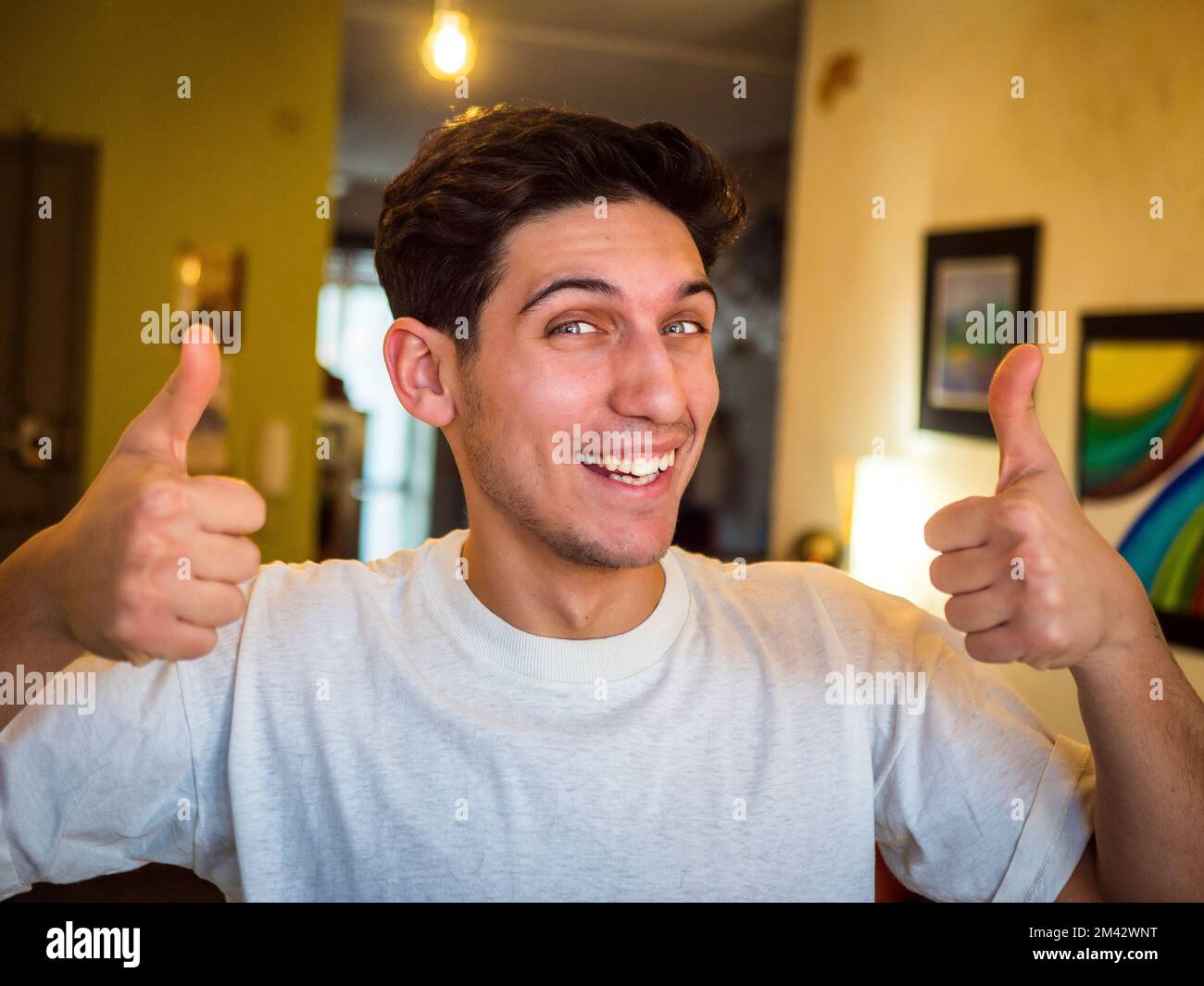 Attractive young man with thumbs up doing OK sign Stock Photo - Alamy