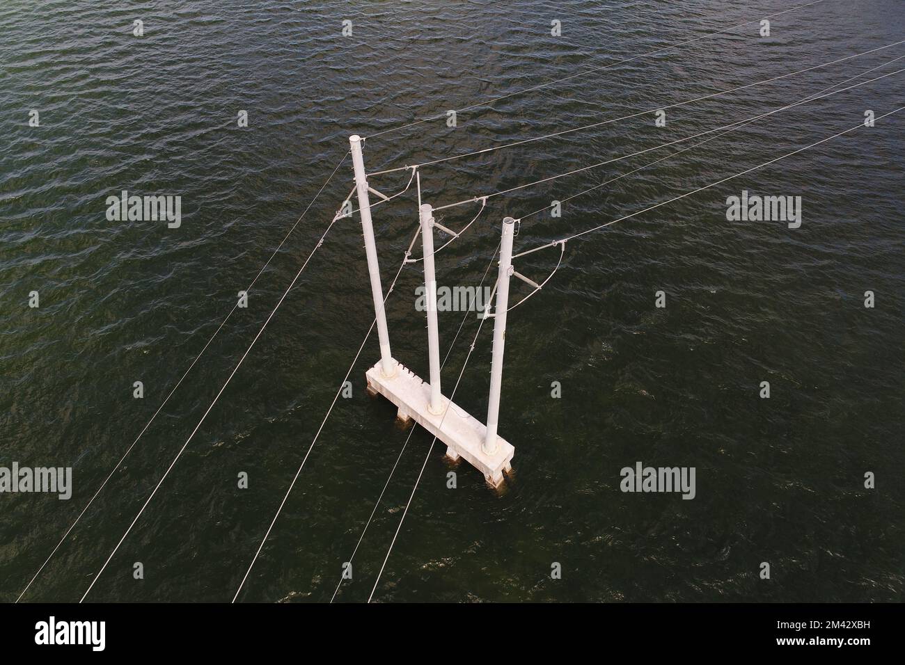 A view of power lines in the middle of a sea during sunrise Stock Photo ...