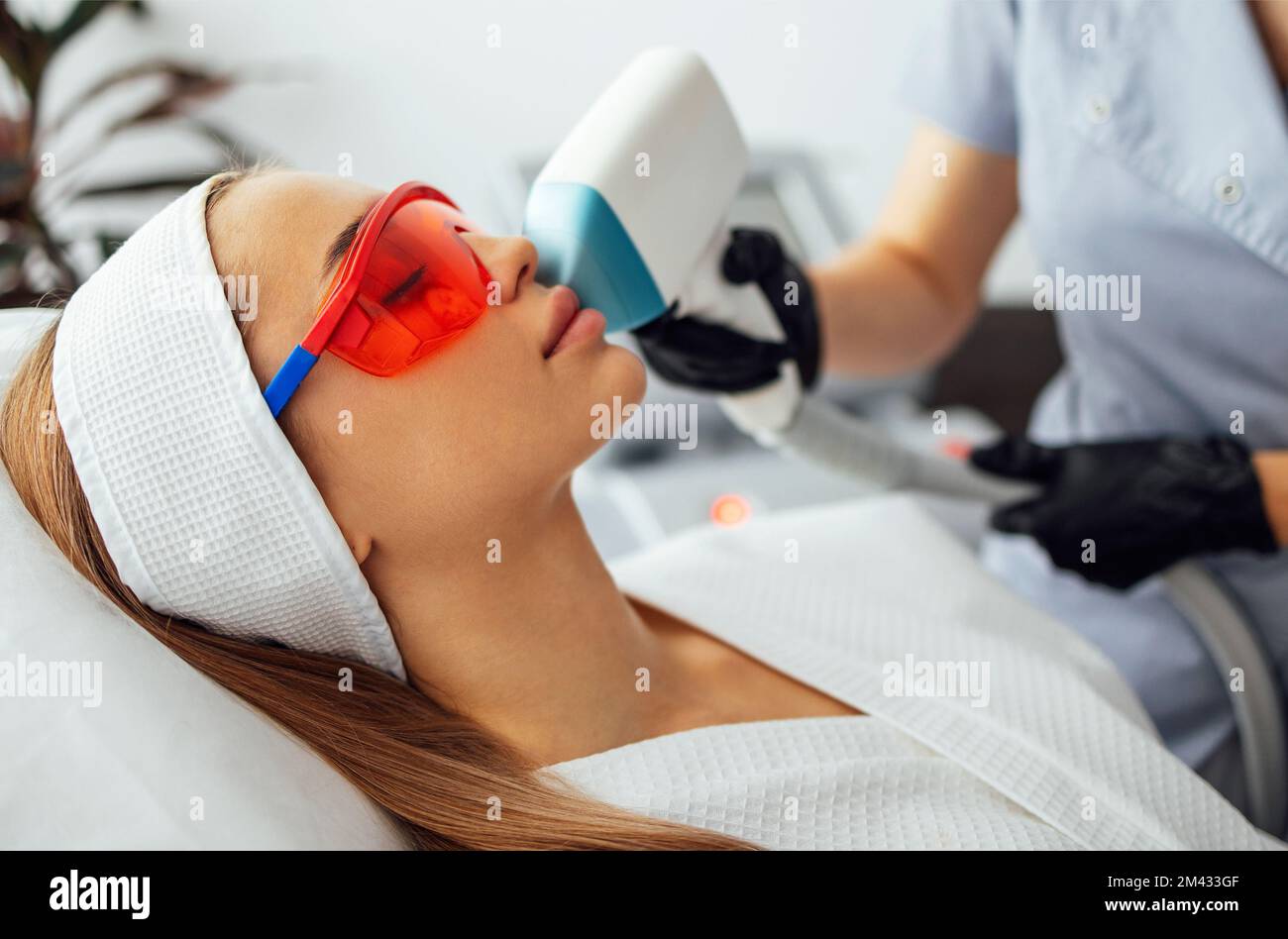 Young woman receiving photo epilation while visiting beauty center on ...