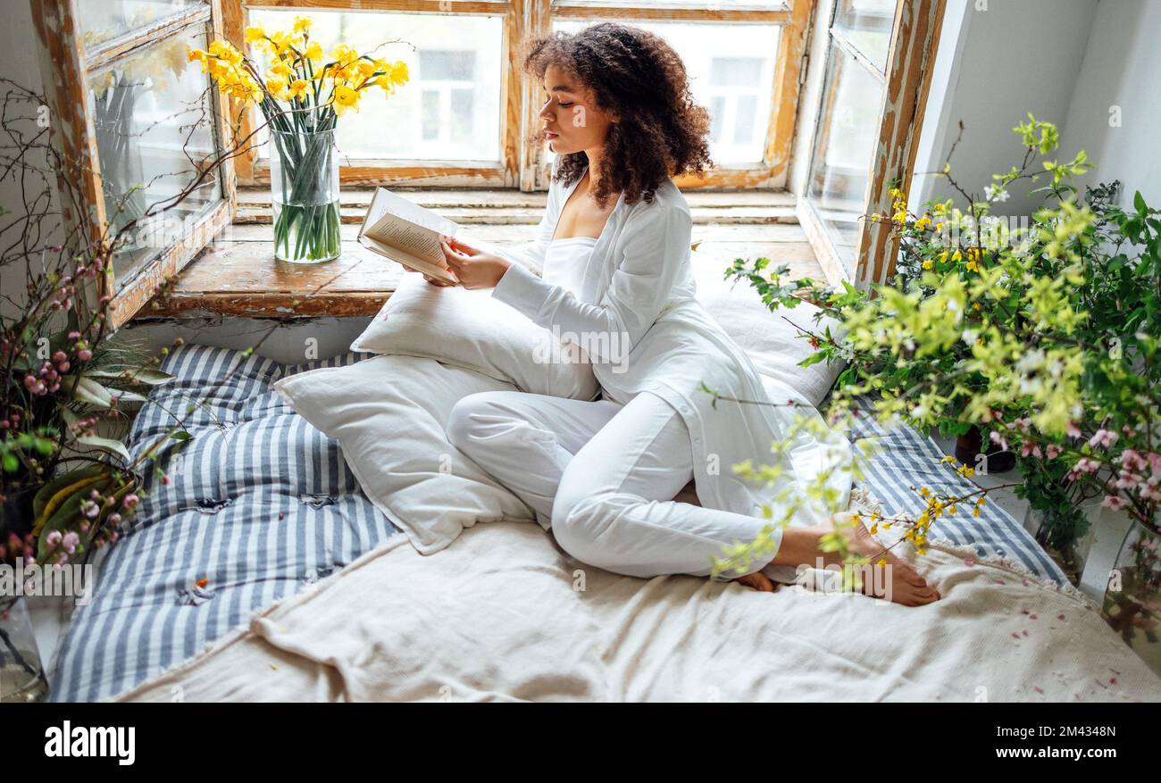 Pretty romantic african american girl, reading book sitting on ...