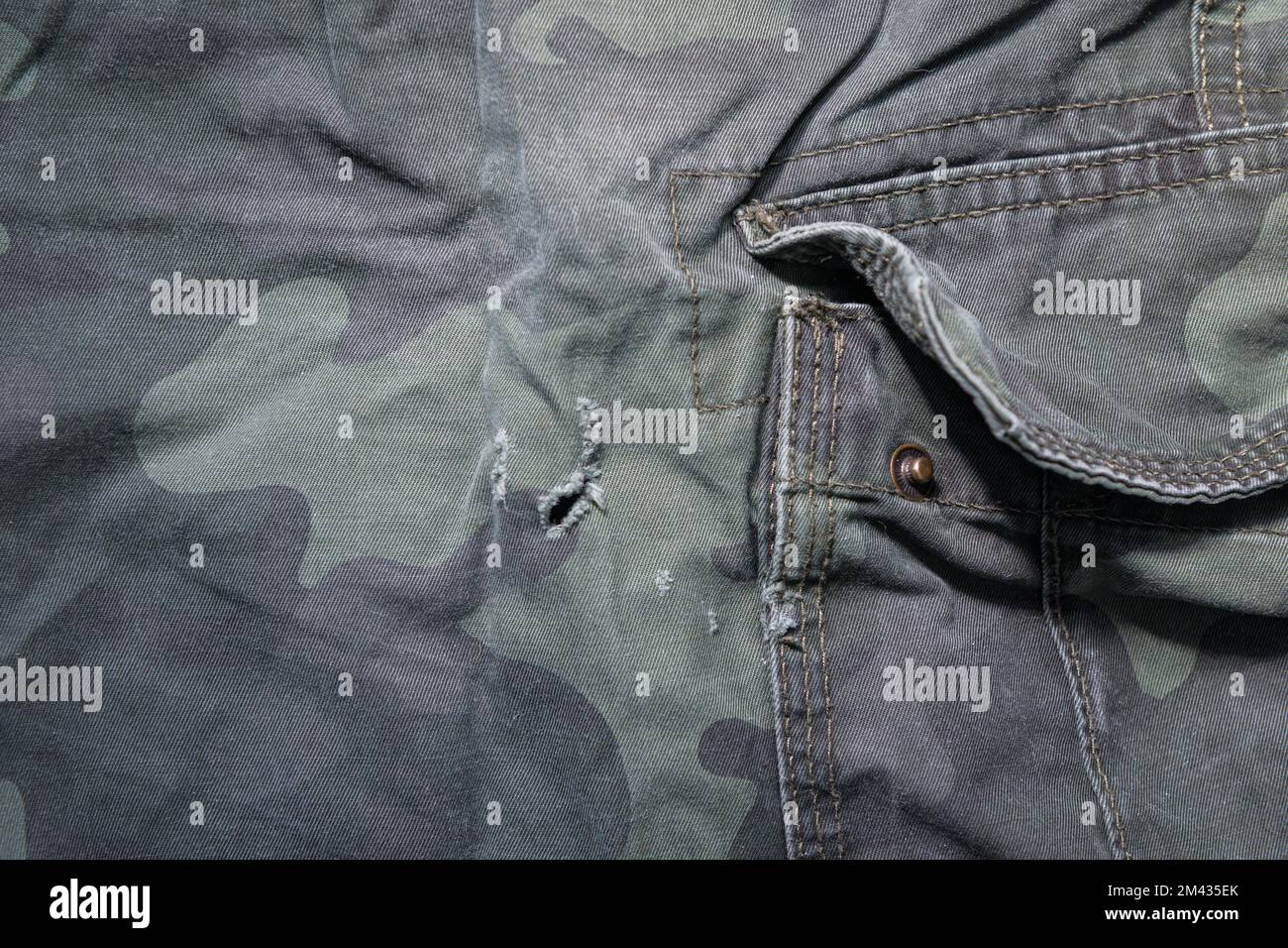 Uniform damaged. A hole in the camouflage fabric Stock Photo - Alamy