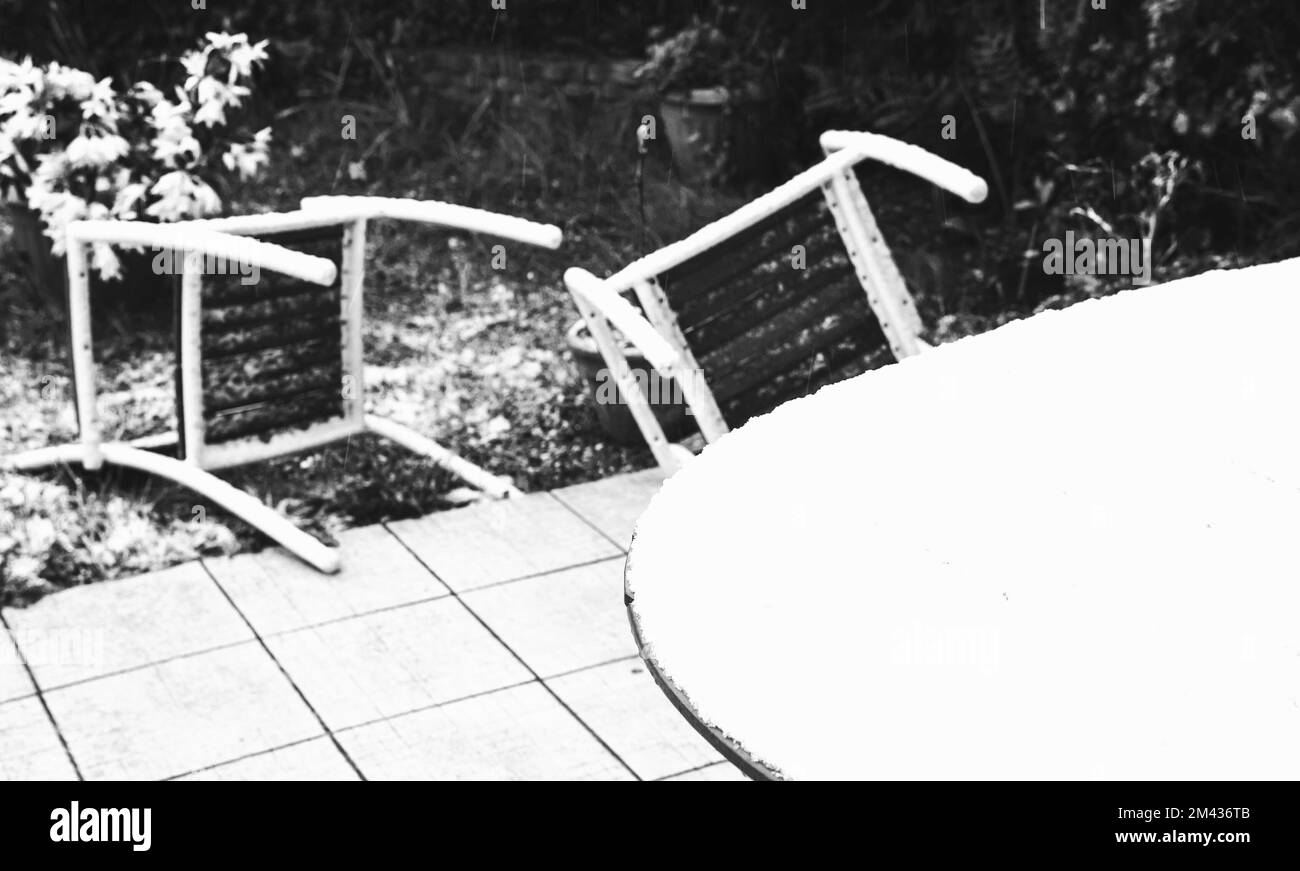 Garden after sudden snow storm in spring. Table covered with snow and ...