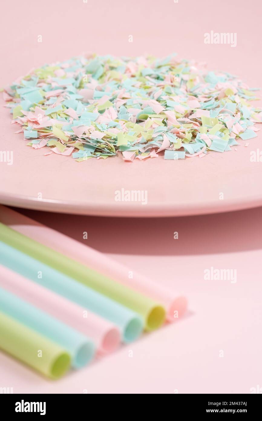 Drinking straws and plate full of microplastics on a pink background ...