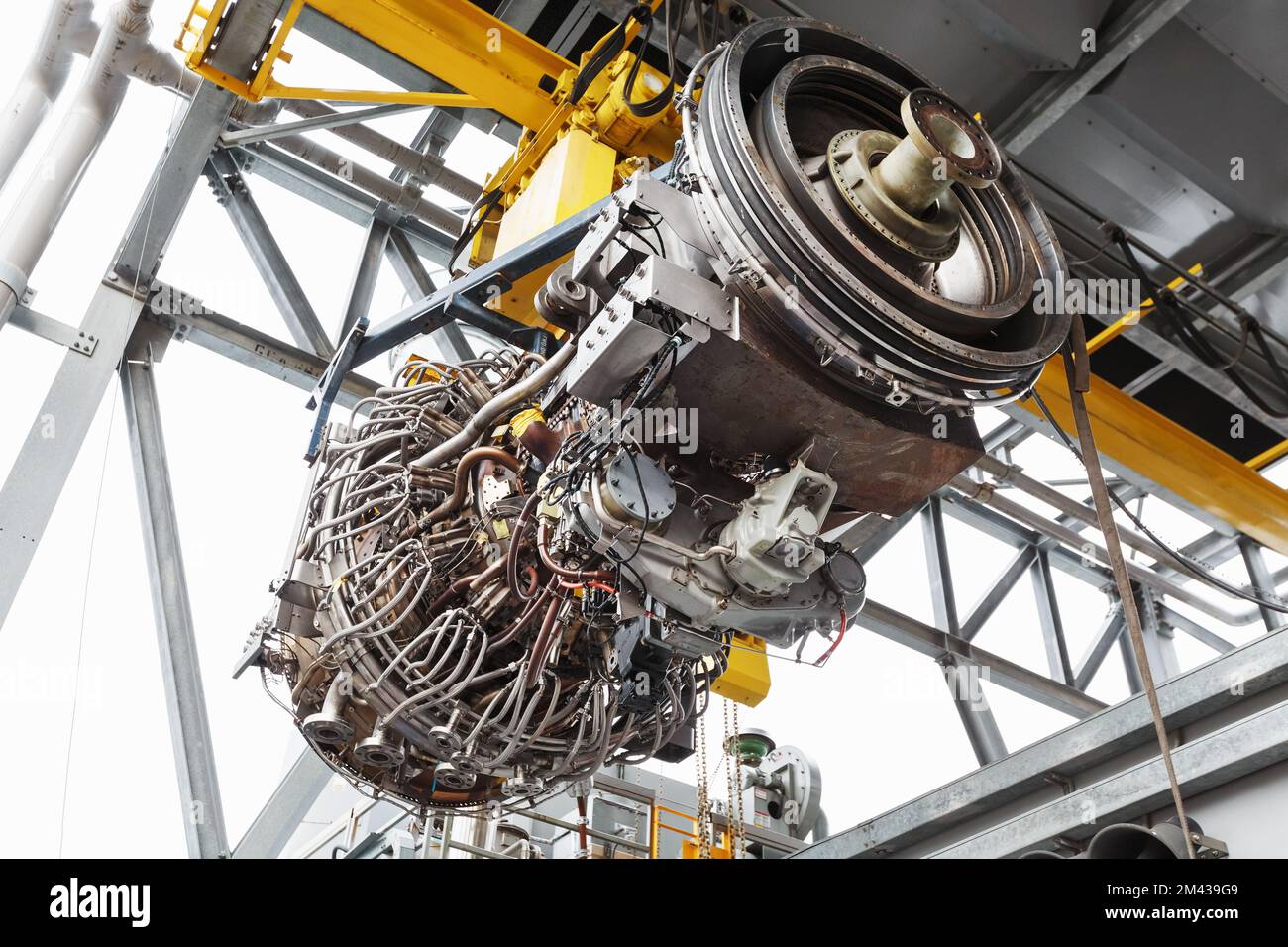 The engine of a gas turbine compressor hangs on a crane during ...