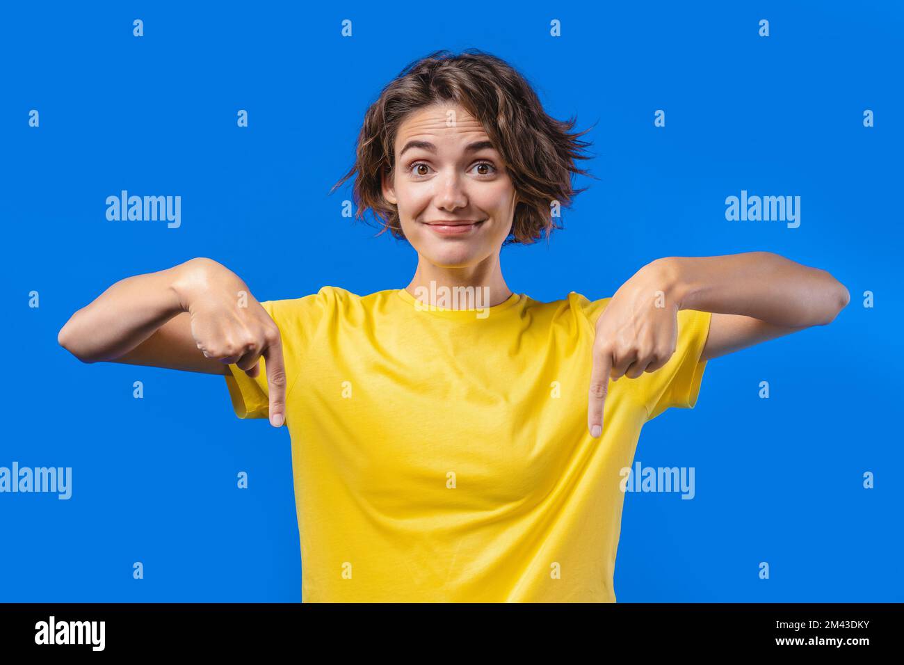 Pretty woman pointing down to advertising area. Blue background. Young ...