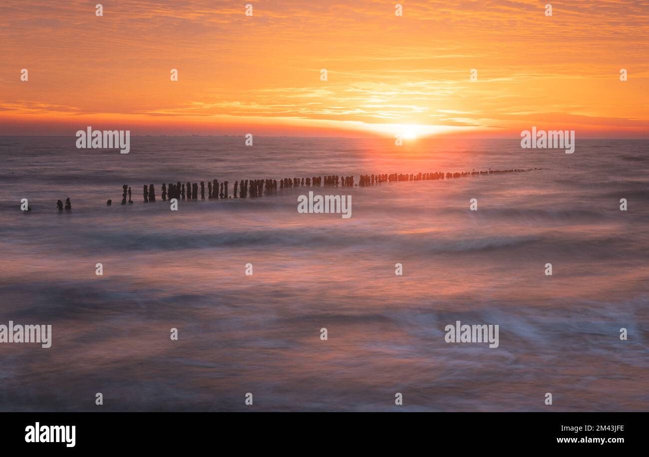 Sunrise over the North sea on East Mersea Island in Essex. Wavebreaker ...