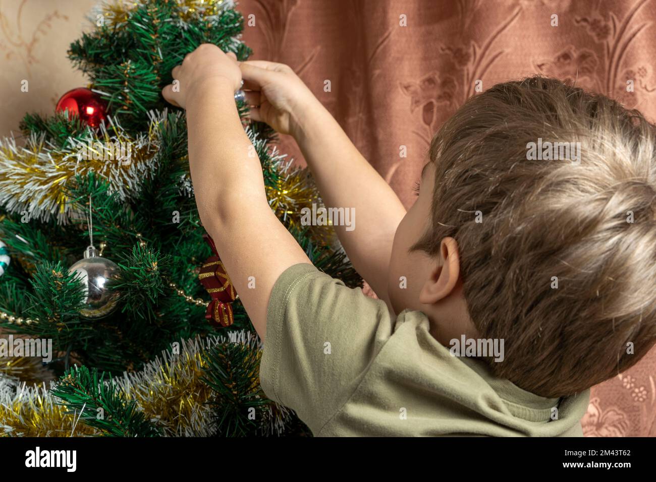 A child dresses up a Christmas tree with toys Stock Photo - Alamy