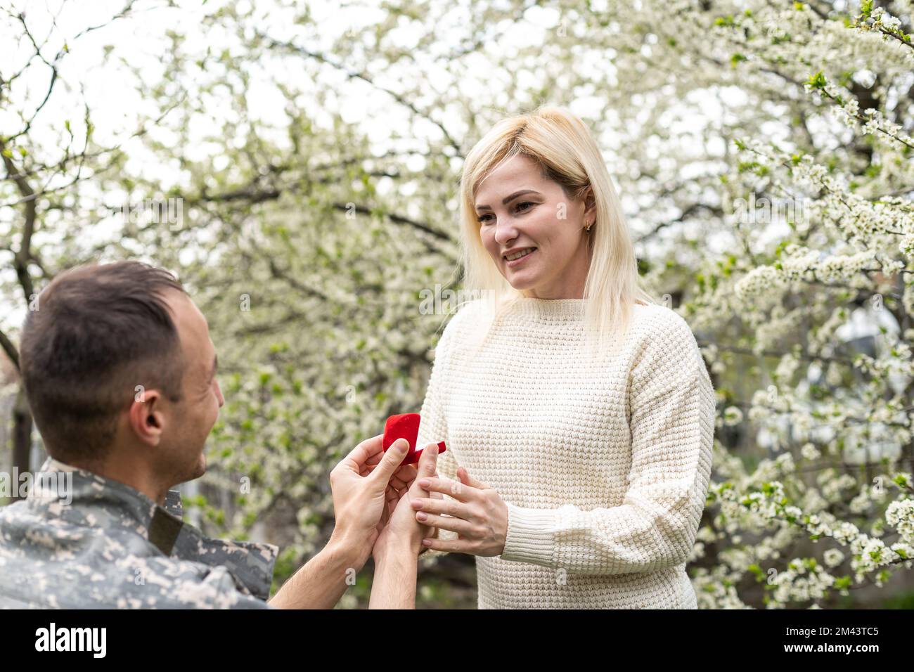 soldier on his knees asking for marriage by holding the hands of his ...
