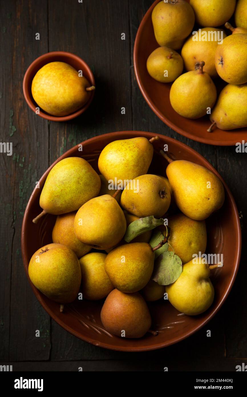 Delicious juicy homemade pears in clay plates on dark background in ...