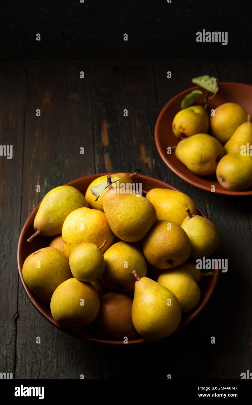 Delicious juicy homemade pears in clay plates on dark background in ...