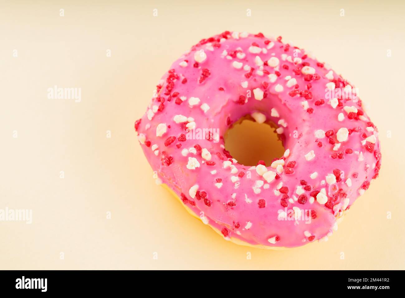 Sweet pink donut with multicolored sprinkles on yellow background ...