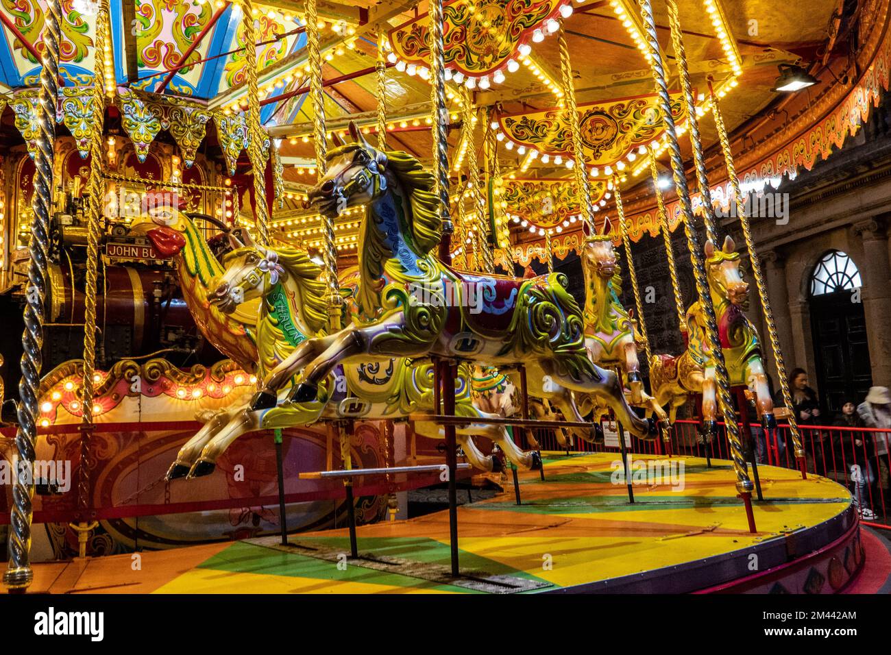 Brightly coloured fairground carousel with galloping ponies. At ...