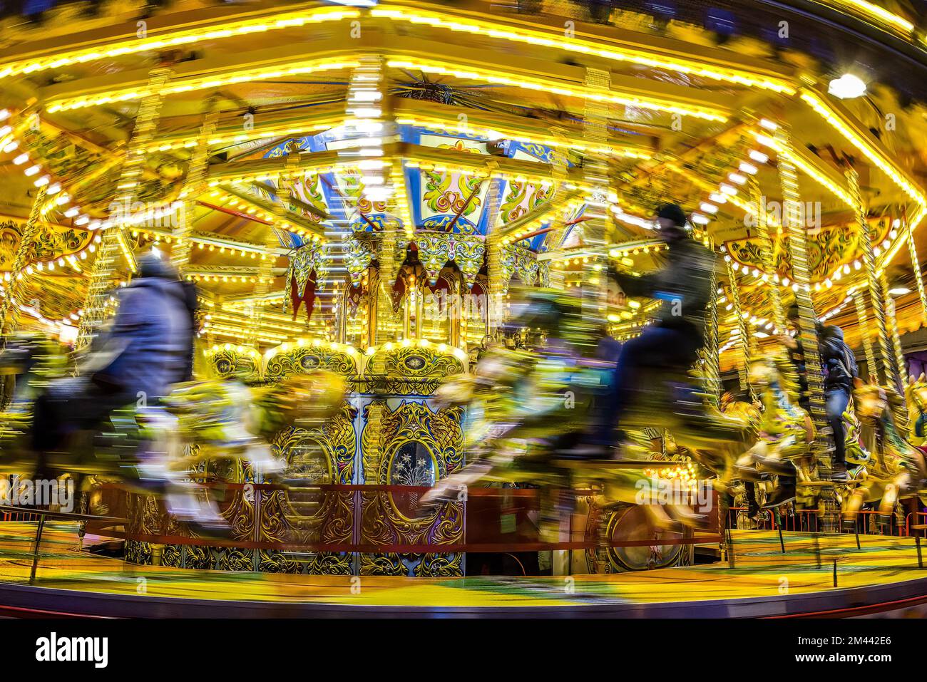 Brightly coloured fairground carousel with galloping ponies. At ...