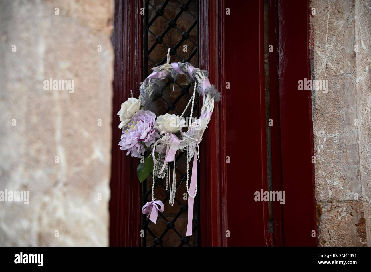 Handmade wreath with silk flowers, lace and pearl beads hanging from a ...