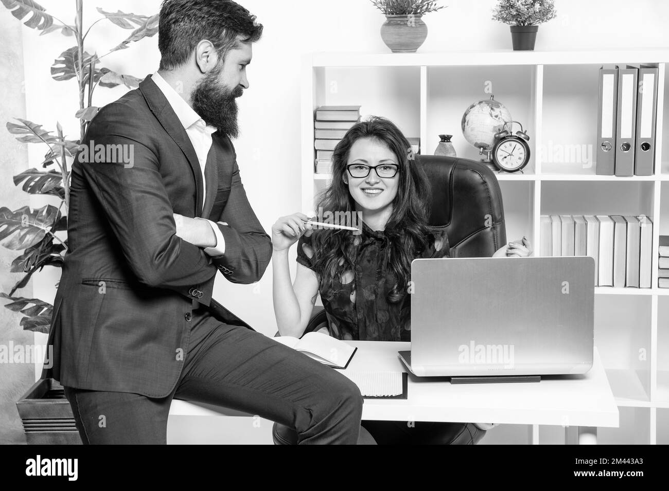 Happy professional woman working while man in suit sitting on office ...