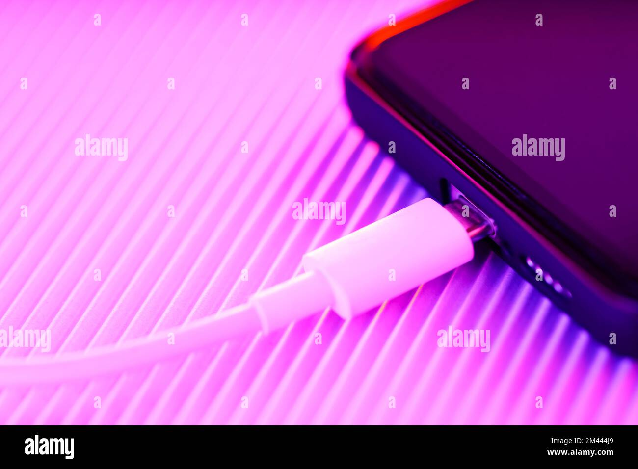 Smartphone charging on a purple background. Mobile phone with connected ...