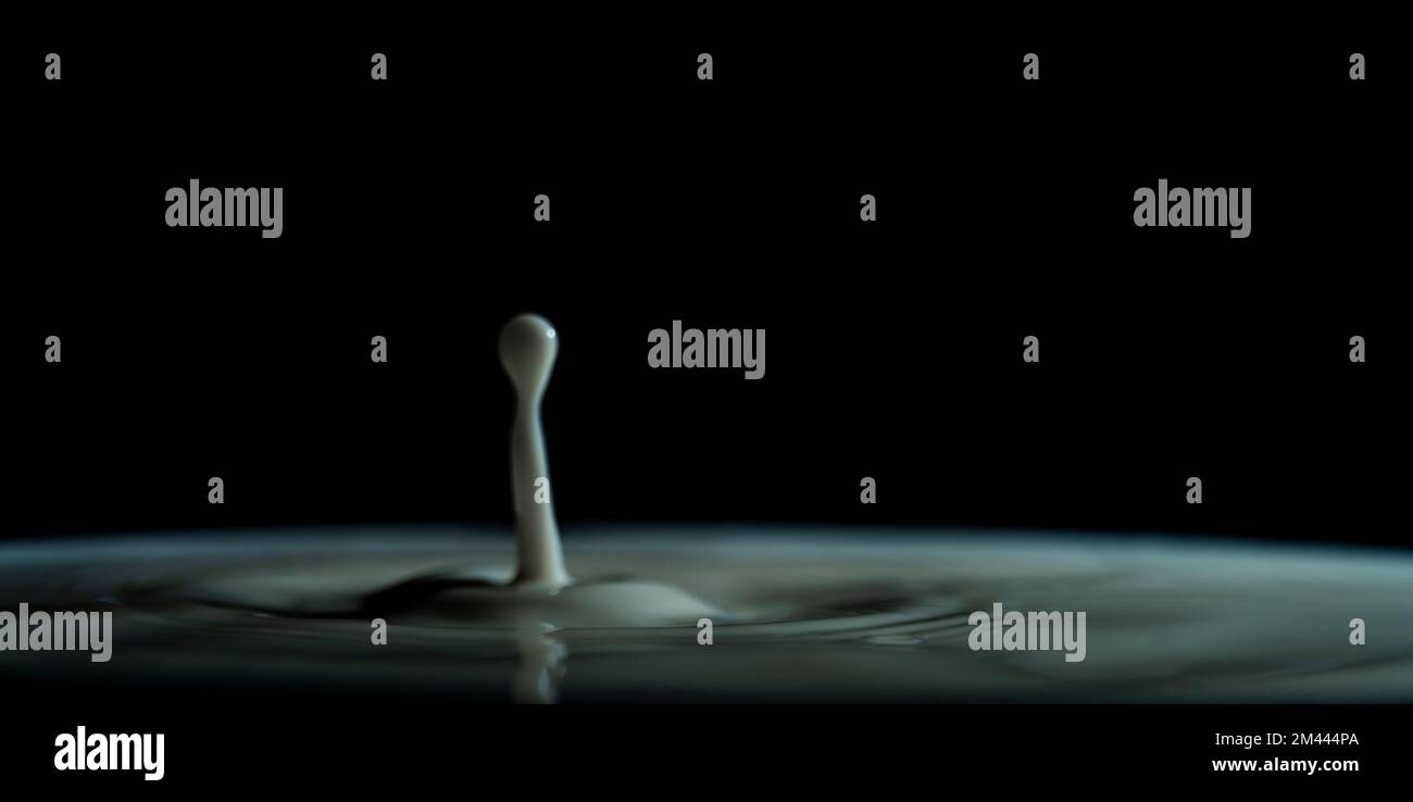 Drop of milk with big waves on surface with dark black background Stock ...