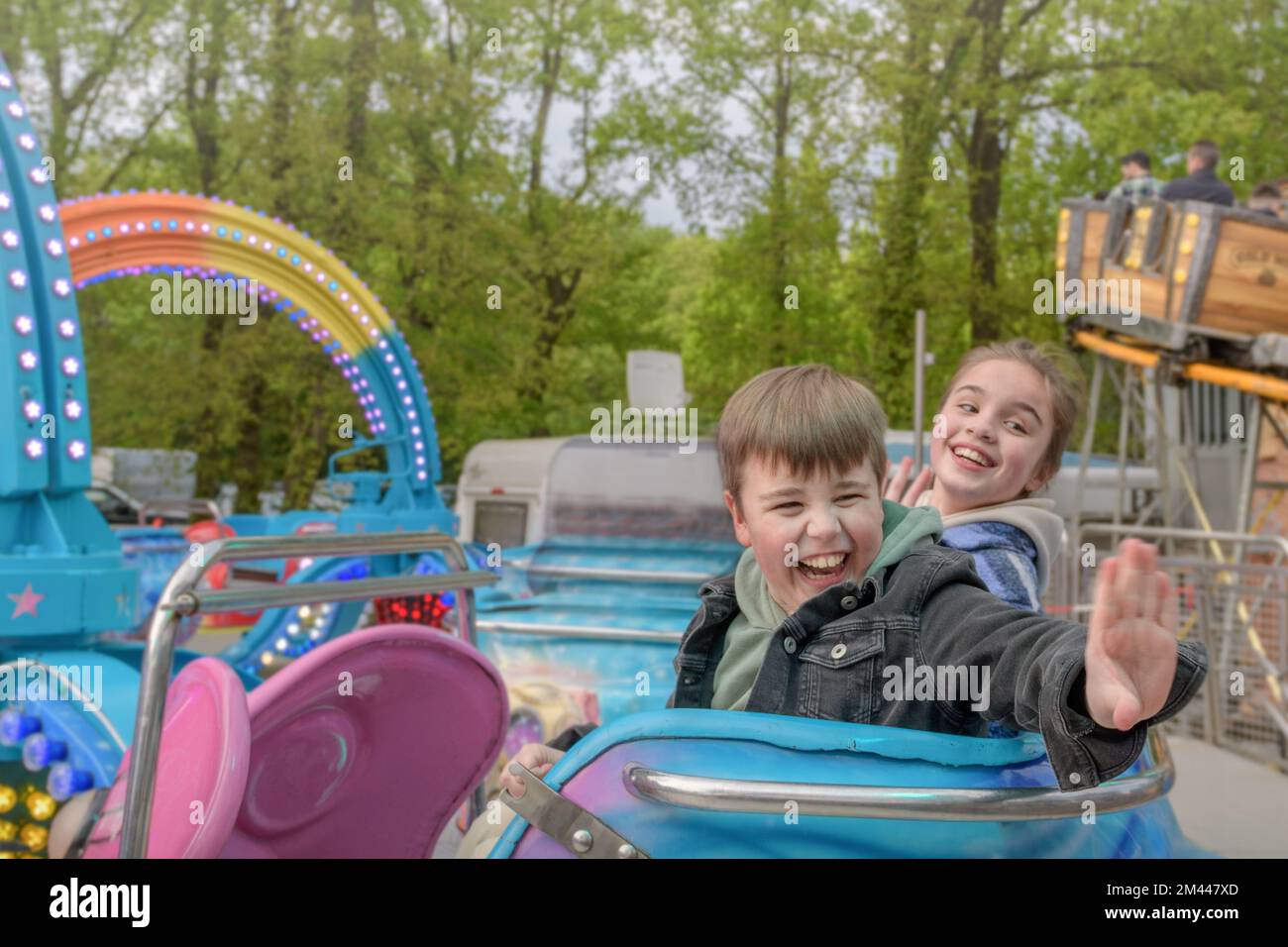 A girl and a boy with real positive emotion оn the carousel in the ...