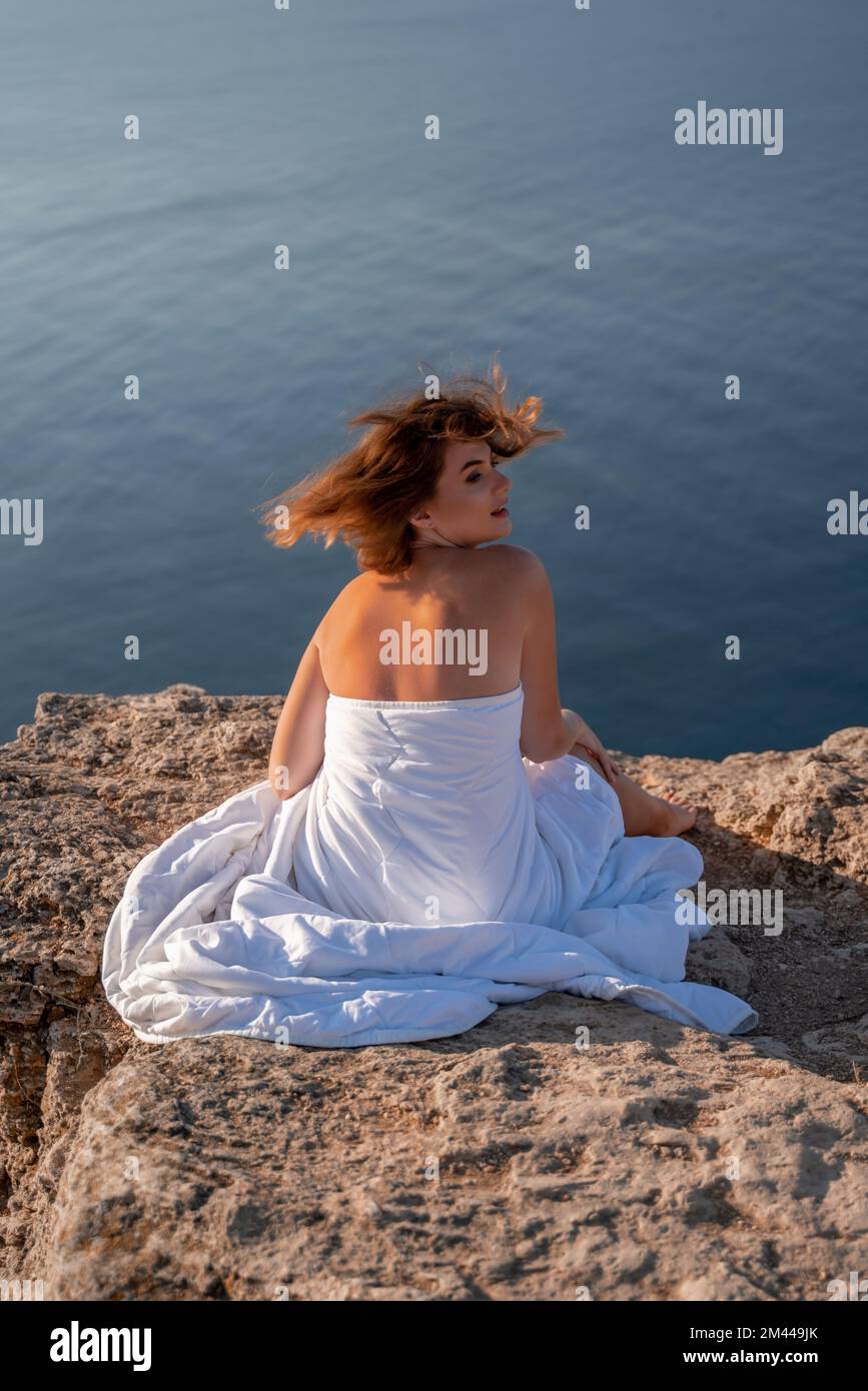 Woman wake up in bed wuth duvet and pillow over nature sea background ...