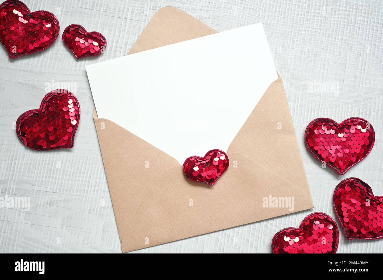 Blank white greeting card with brown envelop and hearts on marble table ...