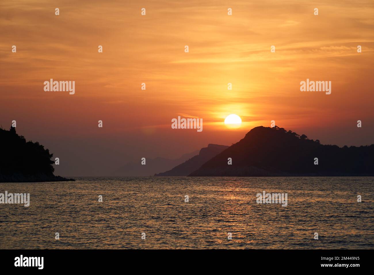 A scenic view of a sunset over the hills and a lake Stock Photo - Alamy