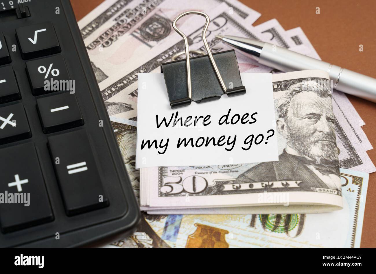 Finance and business concept. On a brown background lies a calculator and dollars on a clip with ...
