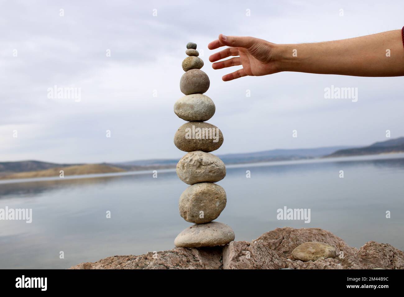 A hand constructs equilibrium on pebbles. Perfect balance of stack of ...