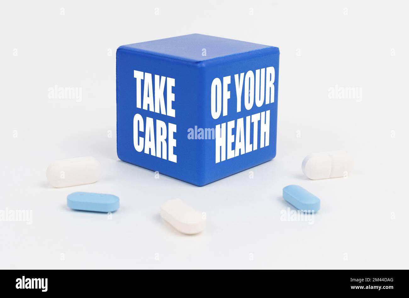 Medicine and health concept. On a white surface are pills and a blue ...