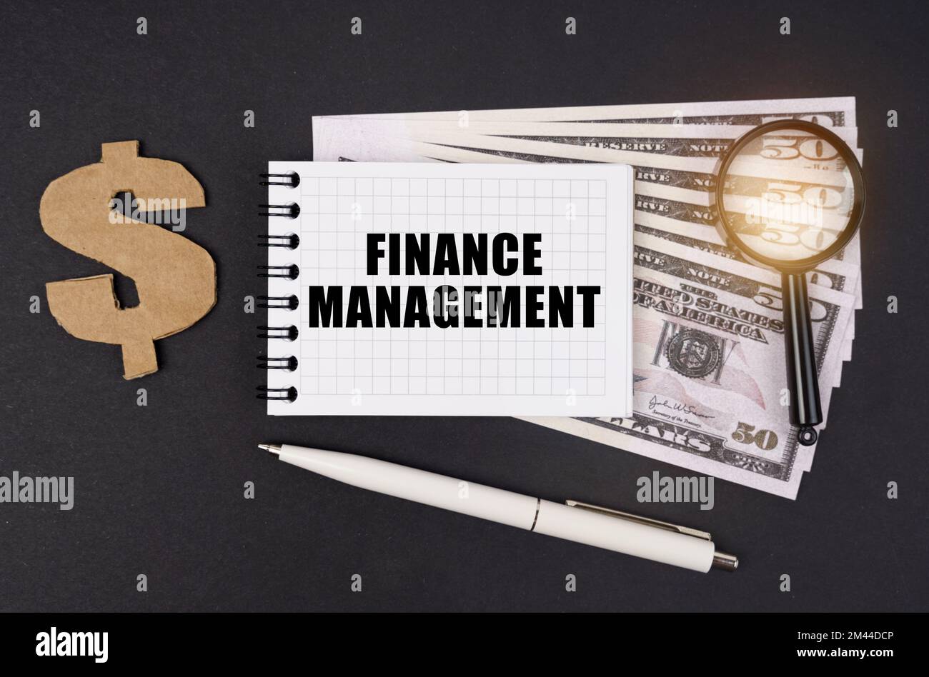 Business and finance concept. On a black surface lie dollars, a symbol, a magnifying glass, a ...