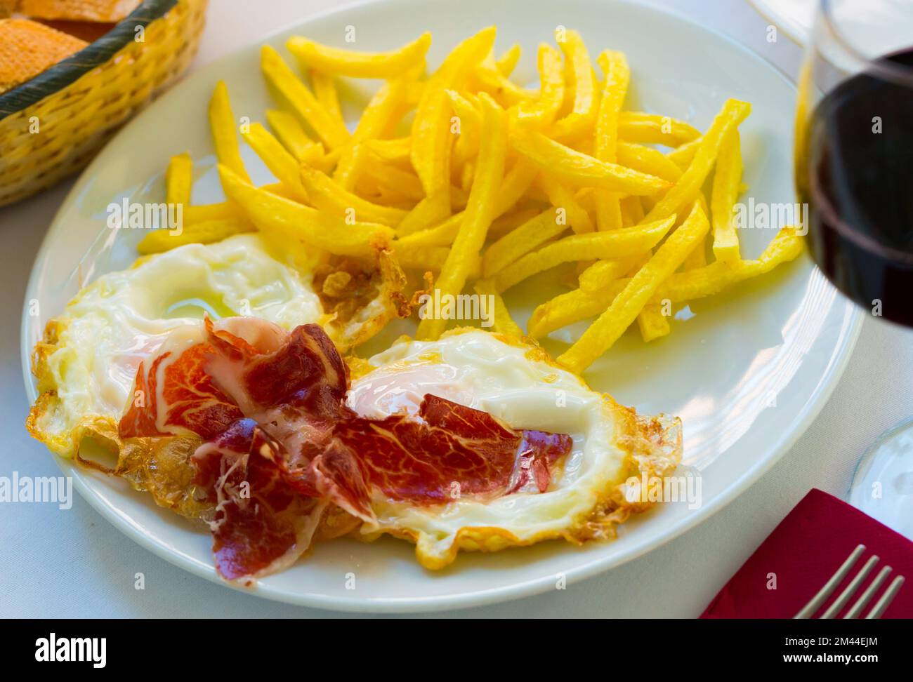 Broken eggs with ham, potatoes, wine Stock Photo - Alamy