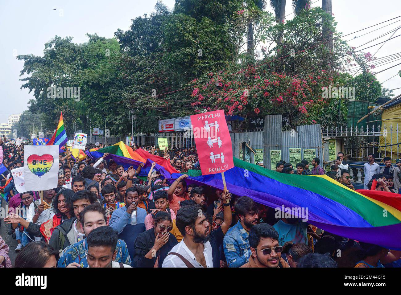 Participants march through the streets while holding huge rainbow flag ...