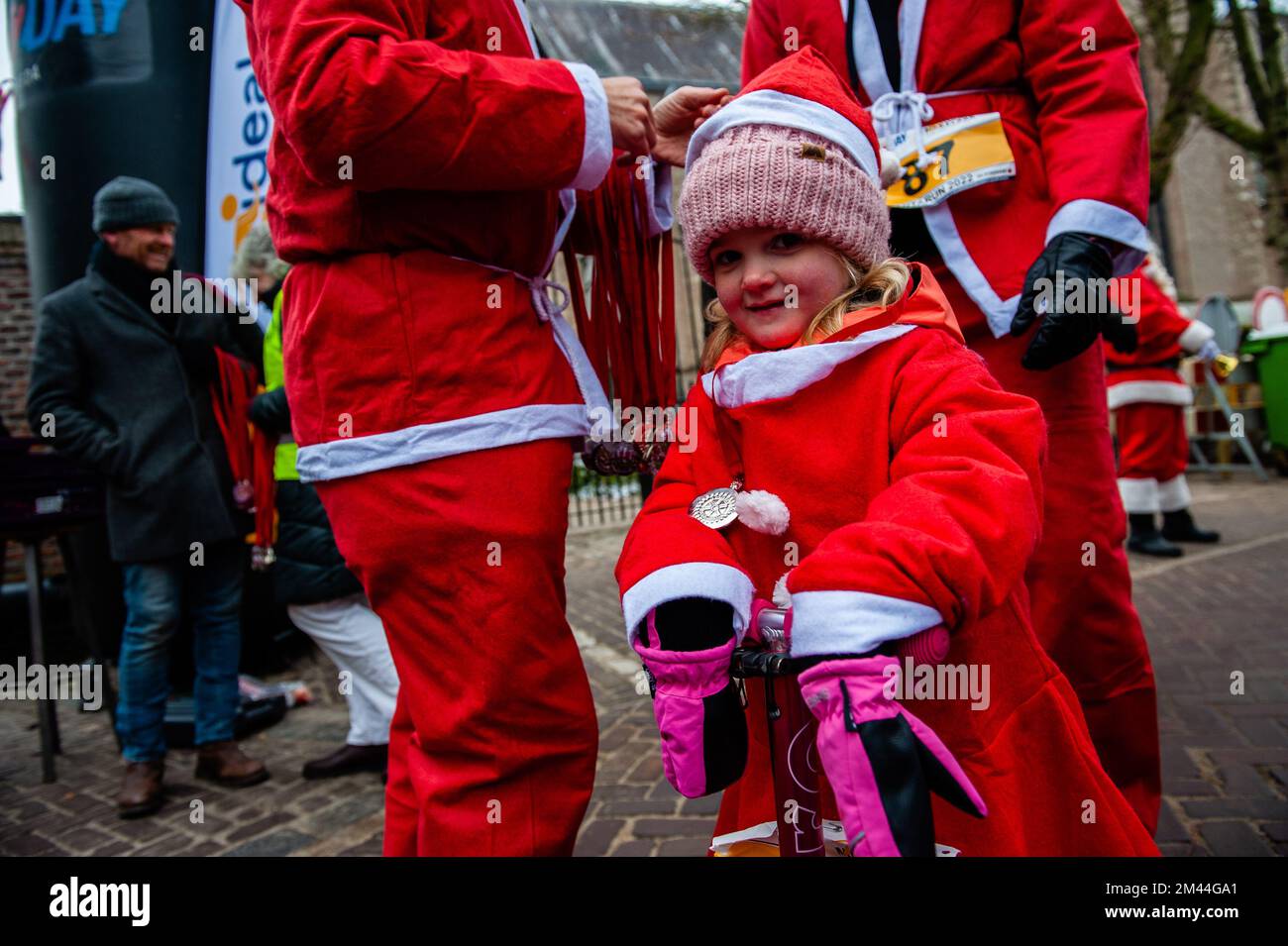 A little girl wearing a Santa costume is seen very happy after ...